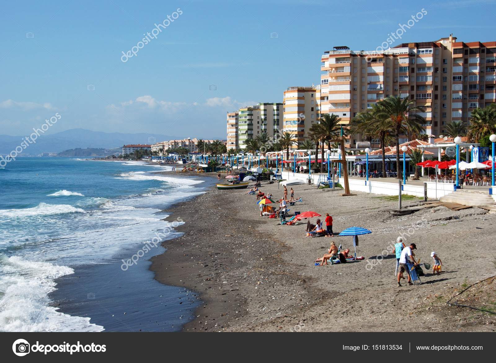 Tourists relaxing on the beach with the promenade and apartments to the ...