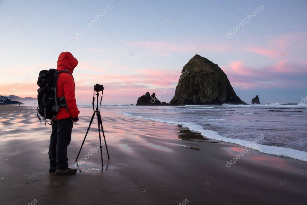 El fotógrafo con una cámara está de pie en la playa de arena durante un ...