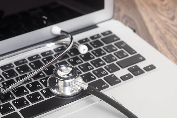 Medical stethoscope with a modern laptop computer on wooden back ...