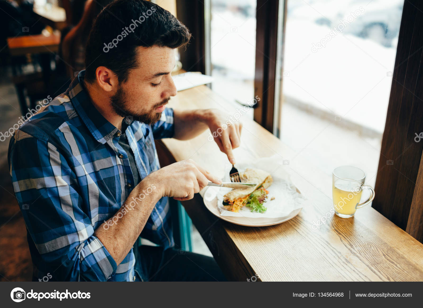 Fotos de Joven guapo almorzando solo en un acogedor restaurante ...