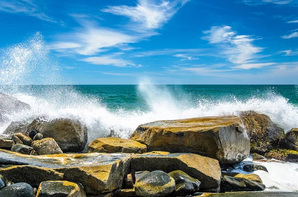 Sea water hitting into rocks on coast and splashing water drops ...