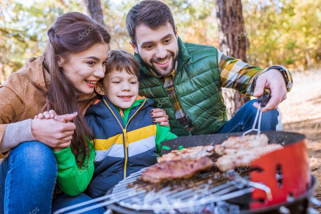 Family grilling meat on barbecue — Stock Photo © RomanPashkovsky #129971562