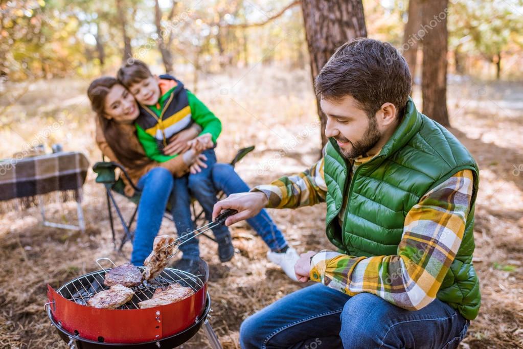 Family grilling meat on barbecue — Stock Photo © RomanPashkovsky #129971606