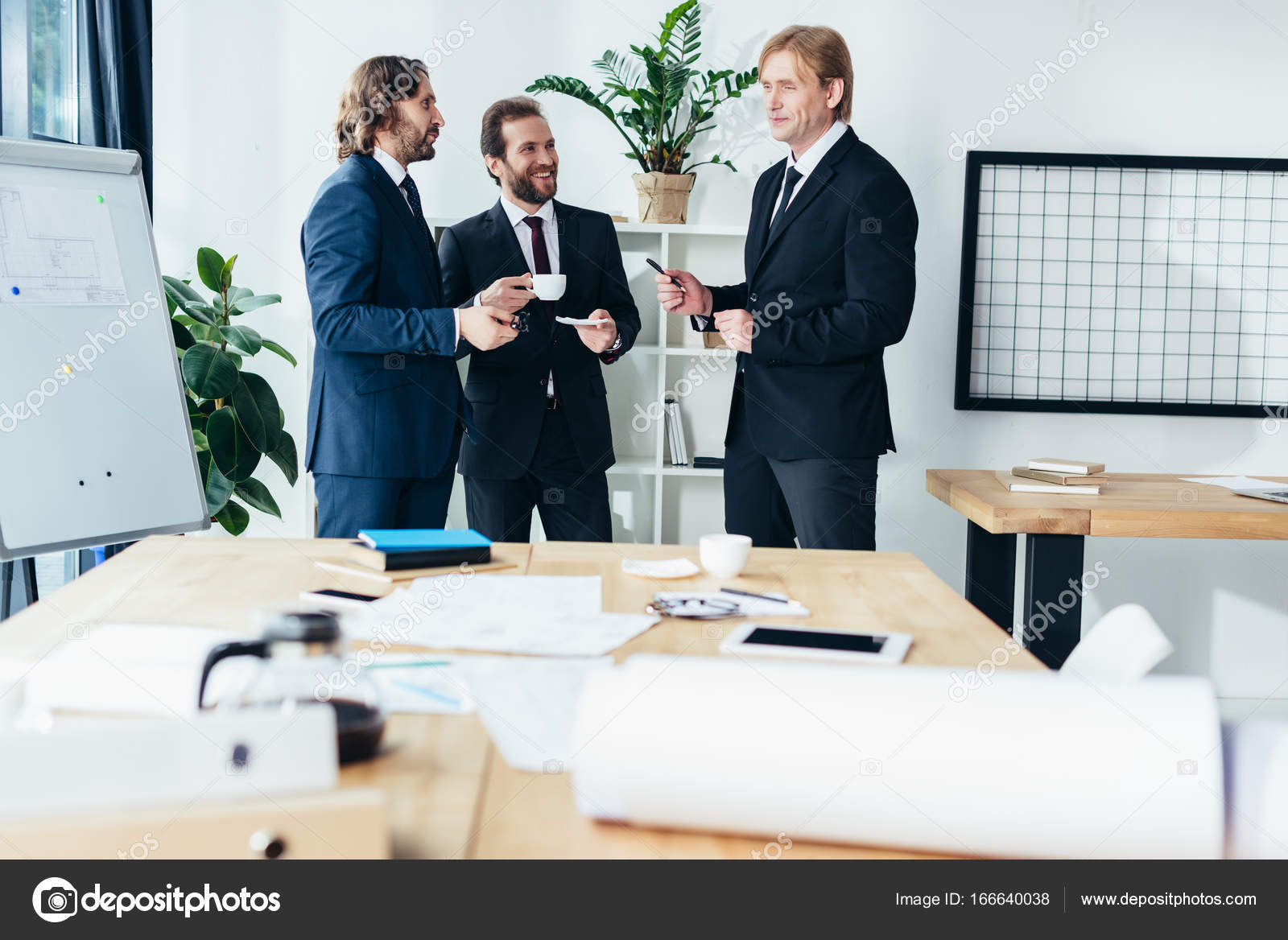 Businessmen talking in office — Stock Photo © ArturVerkhovetskiy #166640038