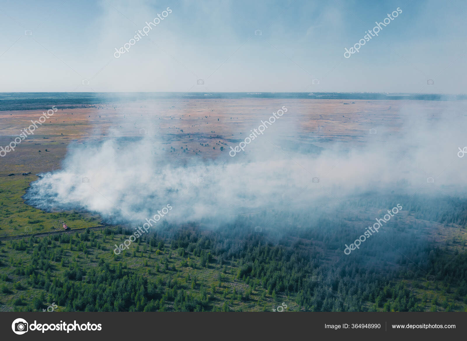 Aerial view of controlled bushfire or fire in forest among green fields ...