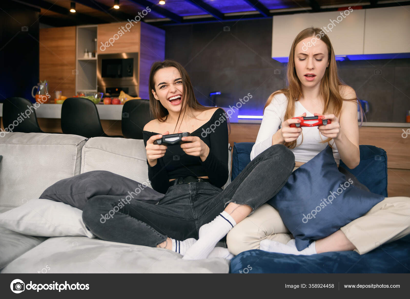 Two girlfriends passionate playing computer games at home while having ...