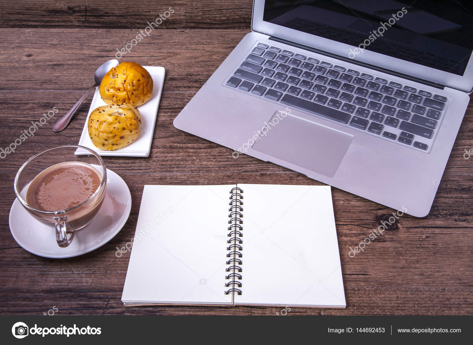 Computer, notebook, tea and bread on wood table for business concept ...