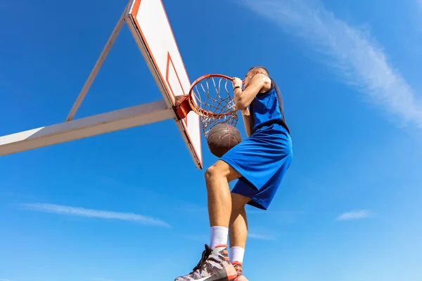 Slam Dunk. Side view of young basketball player making slam dunk ...