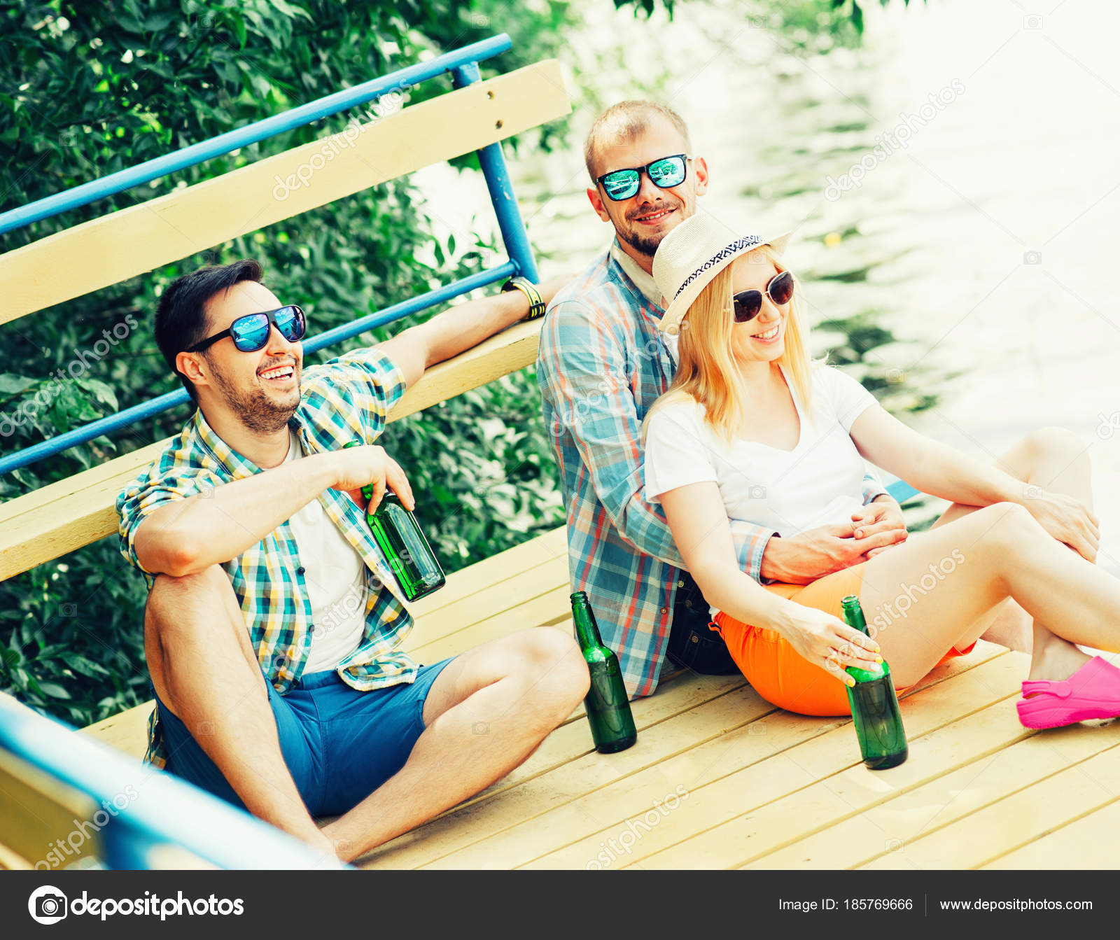 Group of friends two men and woman hanging out on nature with bottles ...
